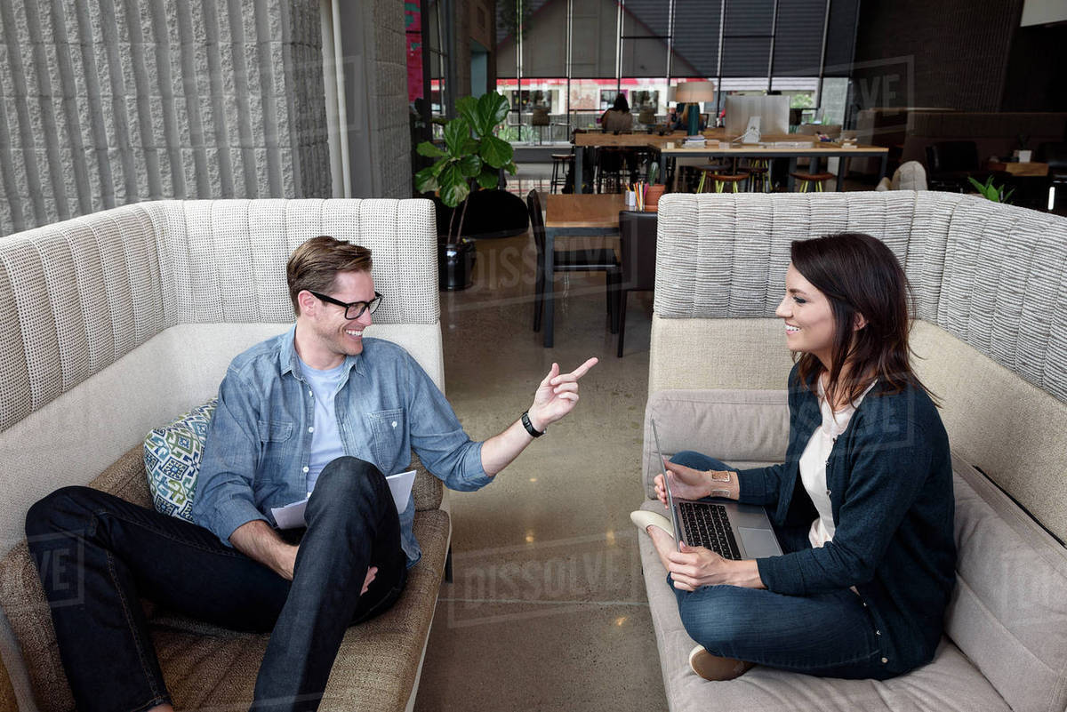 Caucasian couple sitting on sofas talking - Stock Photo - Dissolve