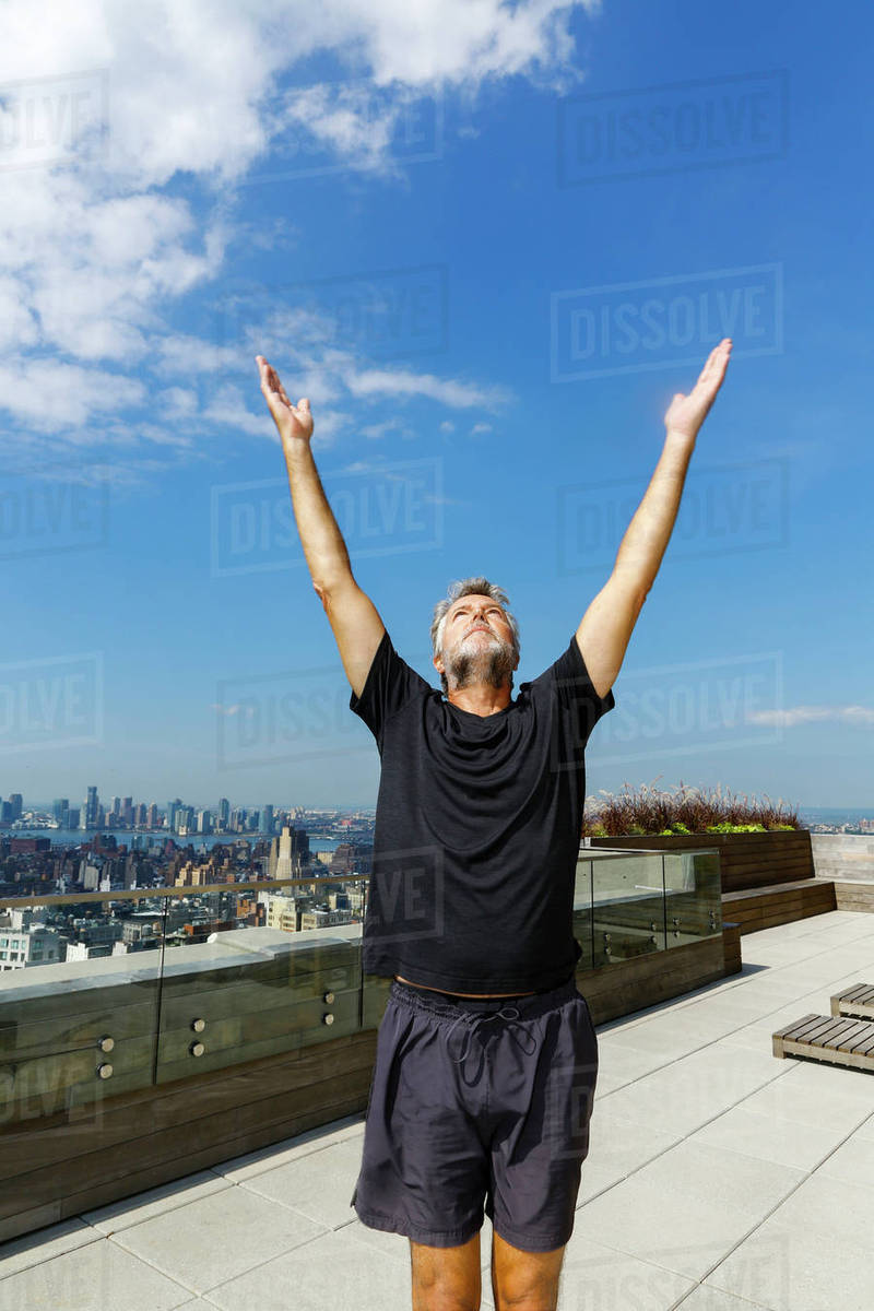 Caucasian man standing with arms raised on urban rooftop - Royalty-free ...