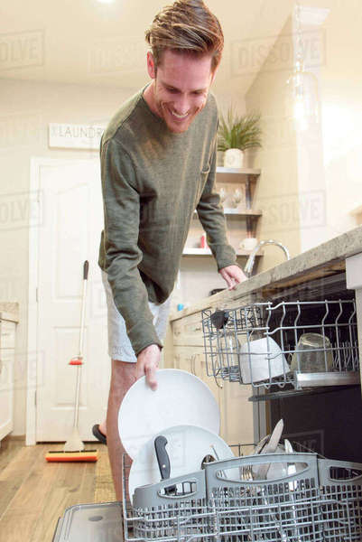 Smiling Caucasian man loading dishwasher - Stock Photo - Dissolve