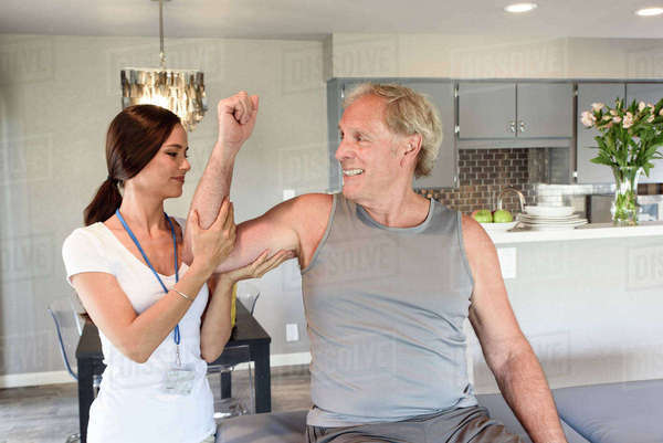 Physical therapist lifting arm of man - Stock Photo - Dissolve