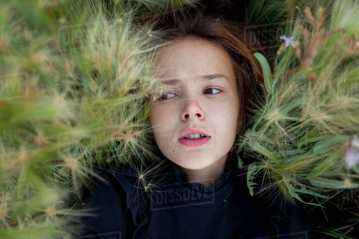 Concerned Caucasian girl laying in field - Stock Photo - Dissolve