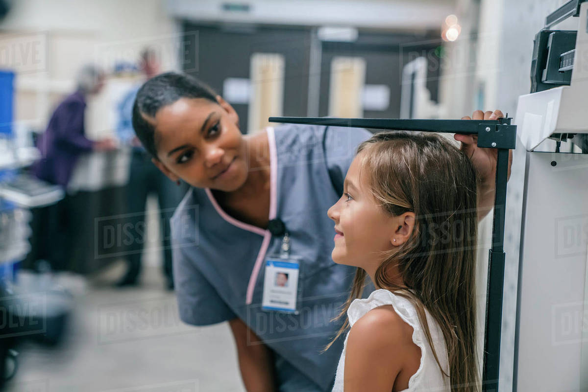 Nurse measuring height of girl - Stock Photo - Dissolve