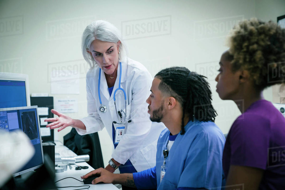 Doctor talking to nurses at computer - Stock Photo - Dissolve