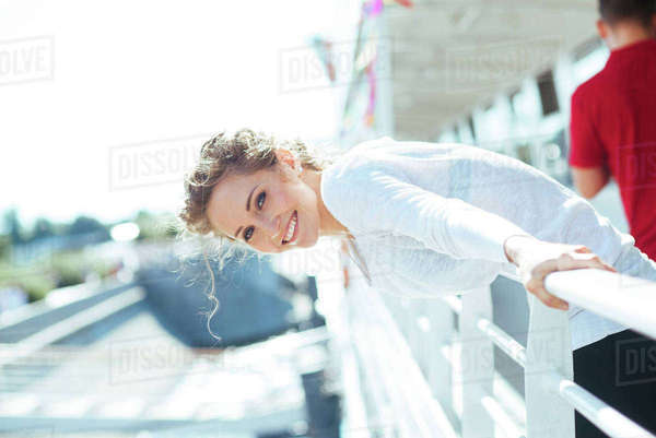 Smiling Caucasian woman leaning over railing - Stock Photo - Dissolve