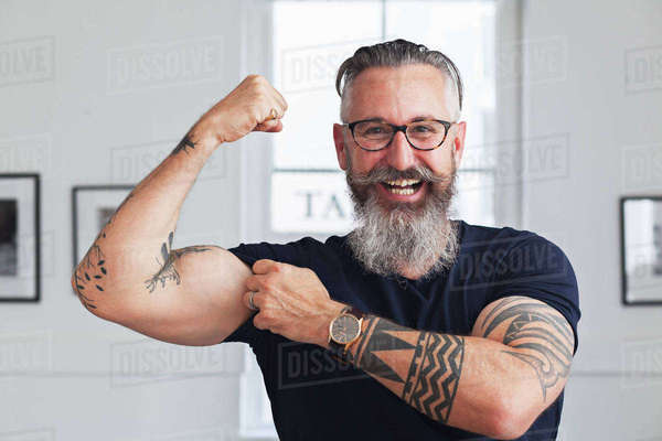 Close up of smiling muscular Caucasian hipster man flexing biceps ...
