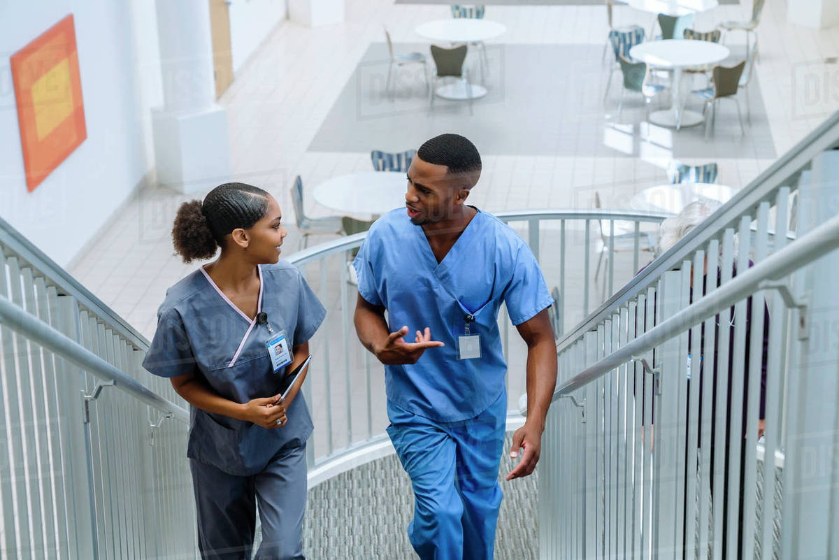 Nurses climbing staircase and talking - Royalty-free Stock Photo | Dissolve