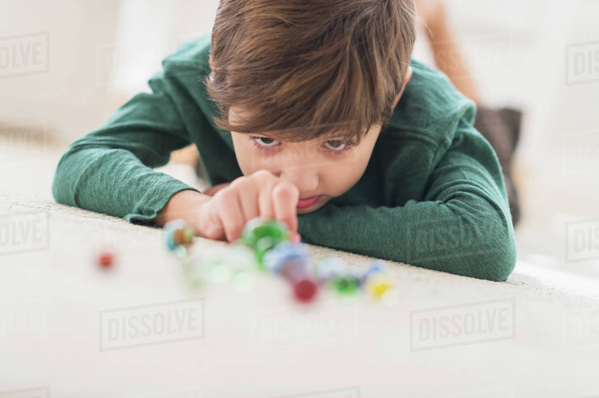 Hispanic boy playing with marbles on bedroom floor - Royalty-free Stock ...