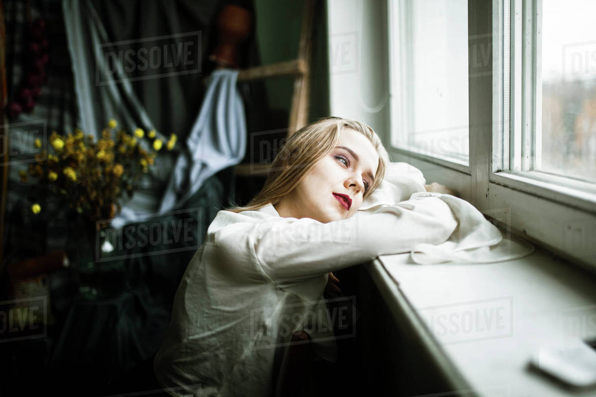 Portrait of pensive Caucasian woman leaning on window sill - Stock ...