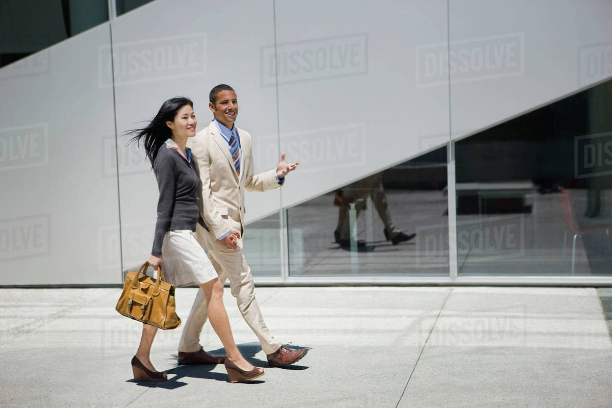 Business people walking and talking outdoors - Stock Photo - Dissolve