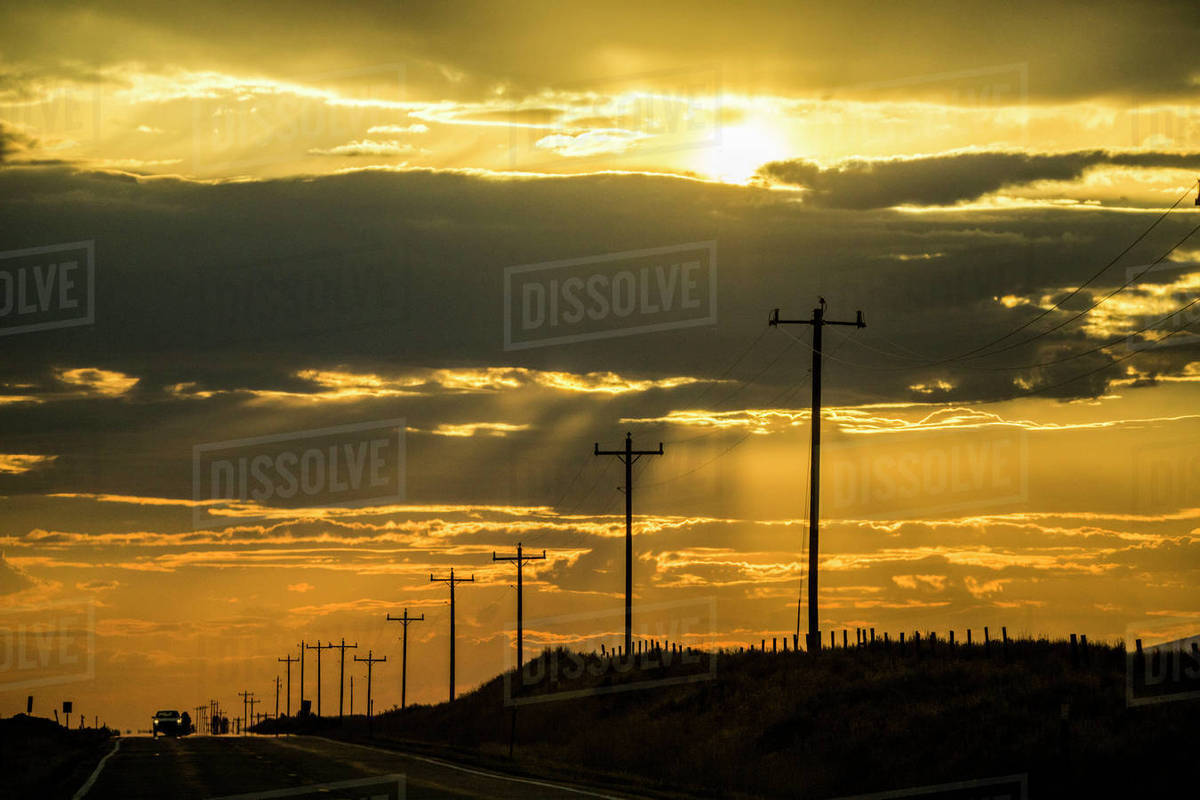 Road and utility poles at sunset - Stock Photo - Dissolve