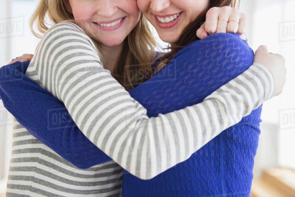 Women hugging in living room - Royalty-free Stock Photo | Dissolve