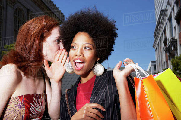 Women whispering on city street - Royalty-free Stock Photo | Dissolve