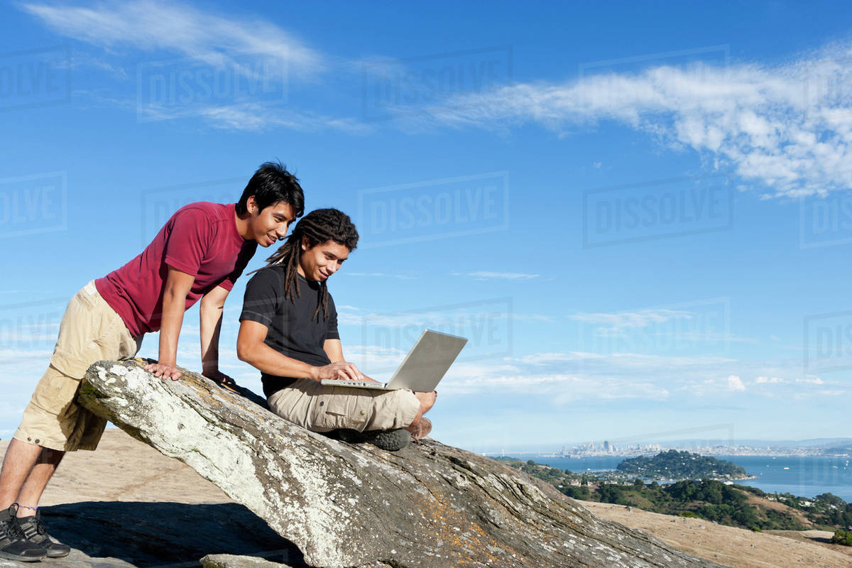 Men using laptop on rocky hilltop - Royalty-free Stock Photo | Dissolve