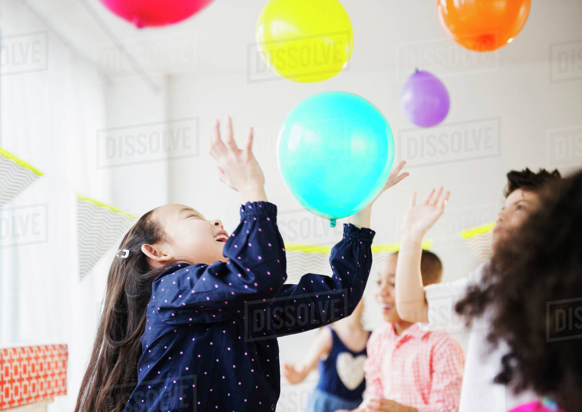 Children playing with colorful balloons at party - Stock Photo - Dissolve