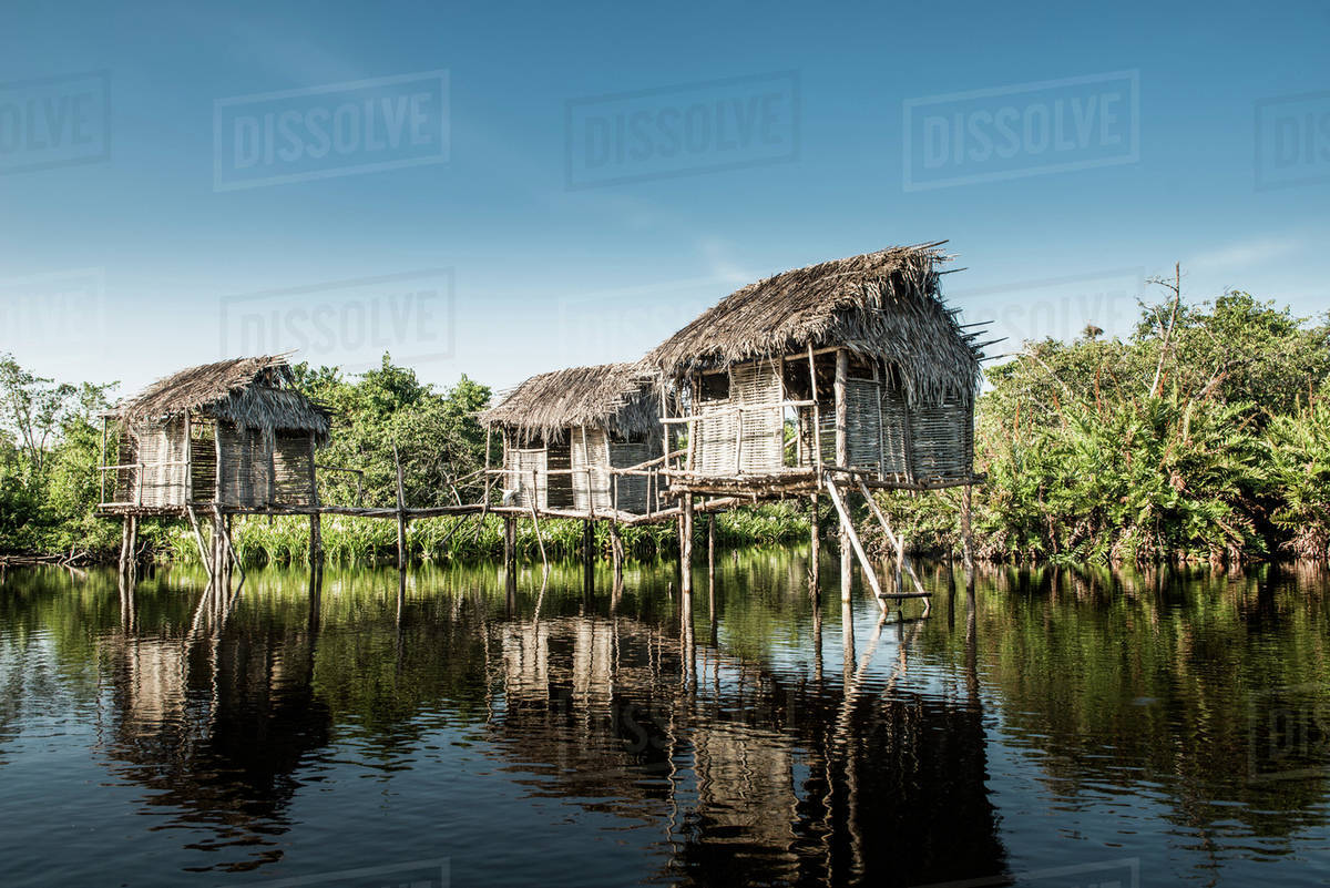 Thatch houses built over rural lake - Royalty-free Stock Photo | Dissolve