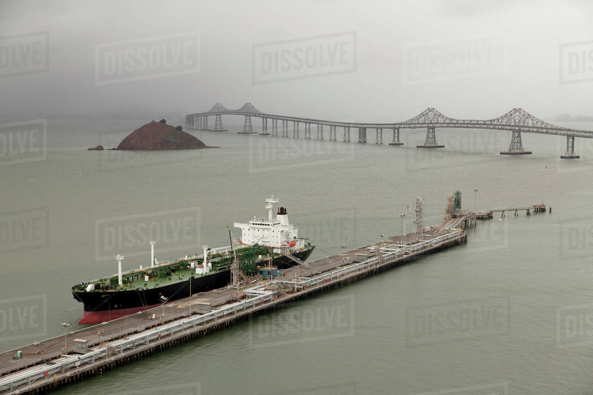 Oil tanker offloading in urban dock - Stock Photo - Dissolve