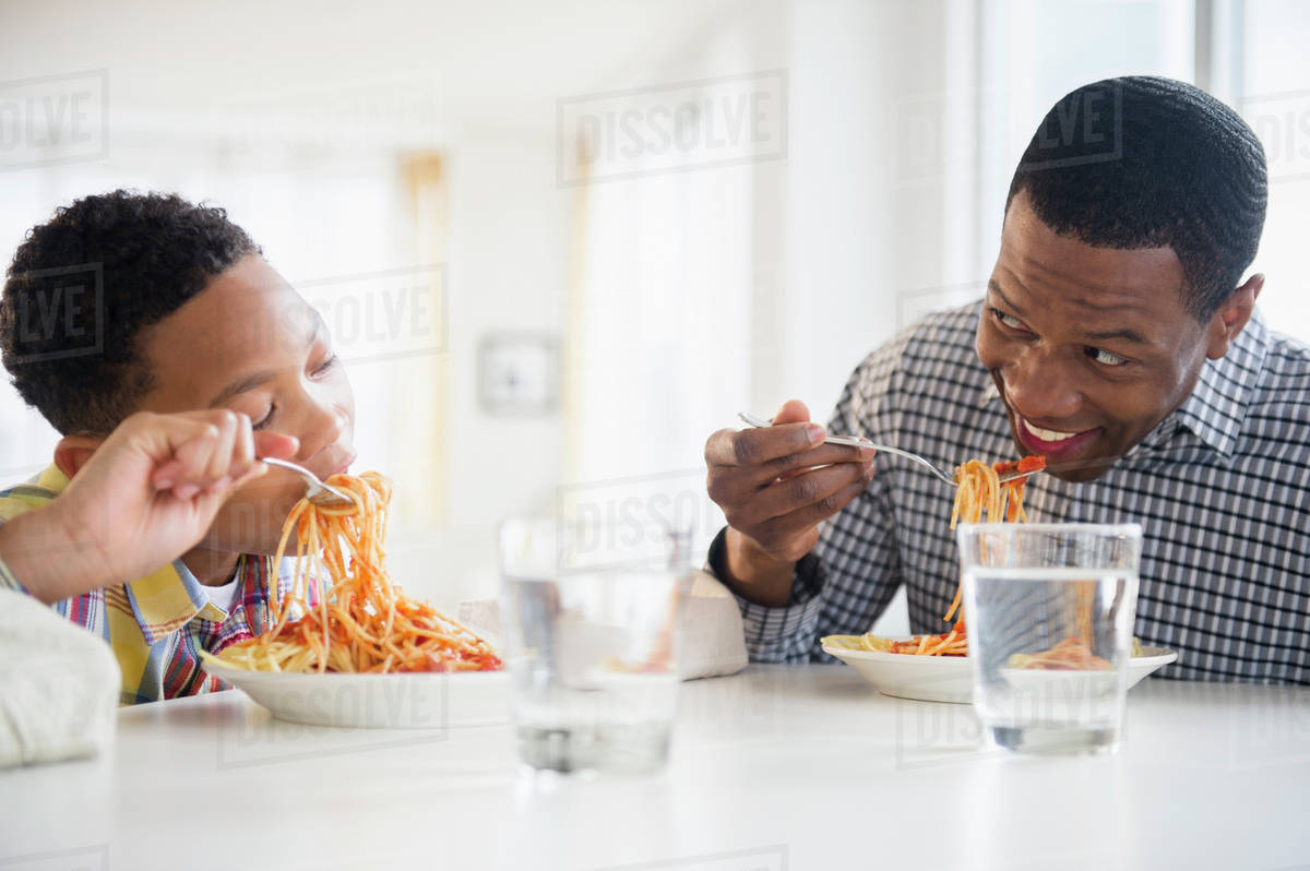 Father and son eating together at table - Stock Photo - Dissolve