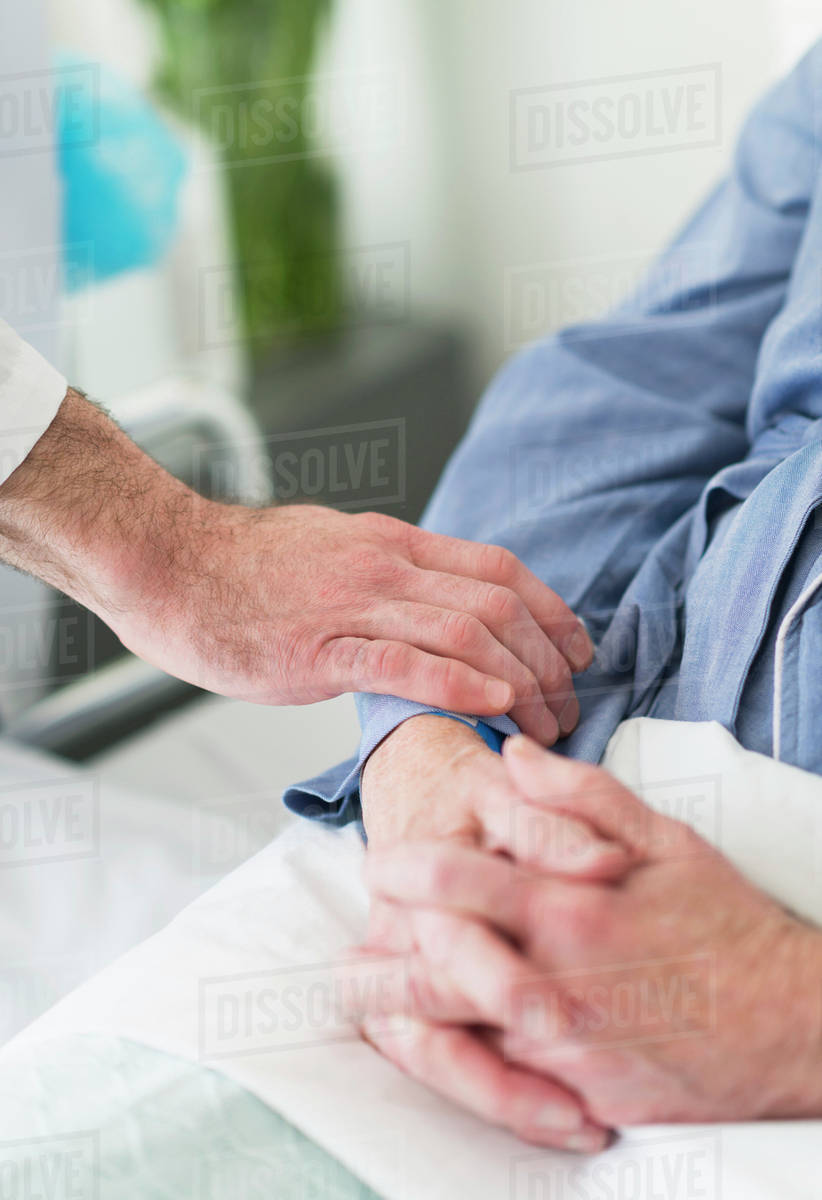 Caucasian doctor reassuring patient in hospital - Stock Photo - Dissolve