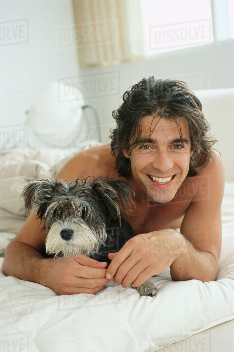 Man hugging dog on bed - Royalty-free Stock Photo | Dissolve