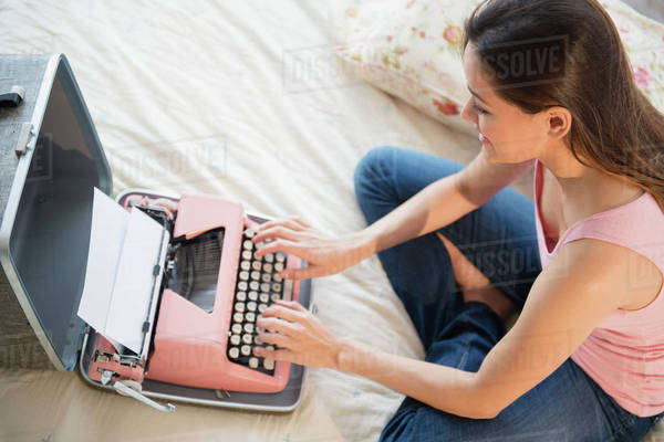 Woman using typewriter on bed - Royalty-free Stock Photo | Dissolve