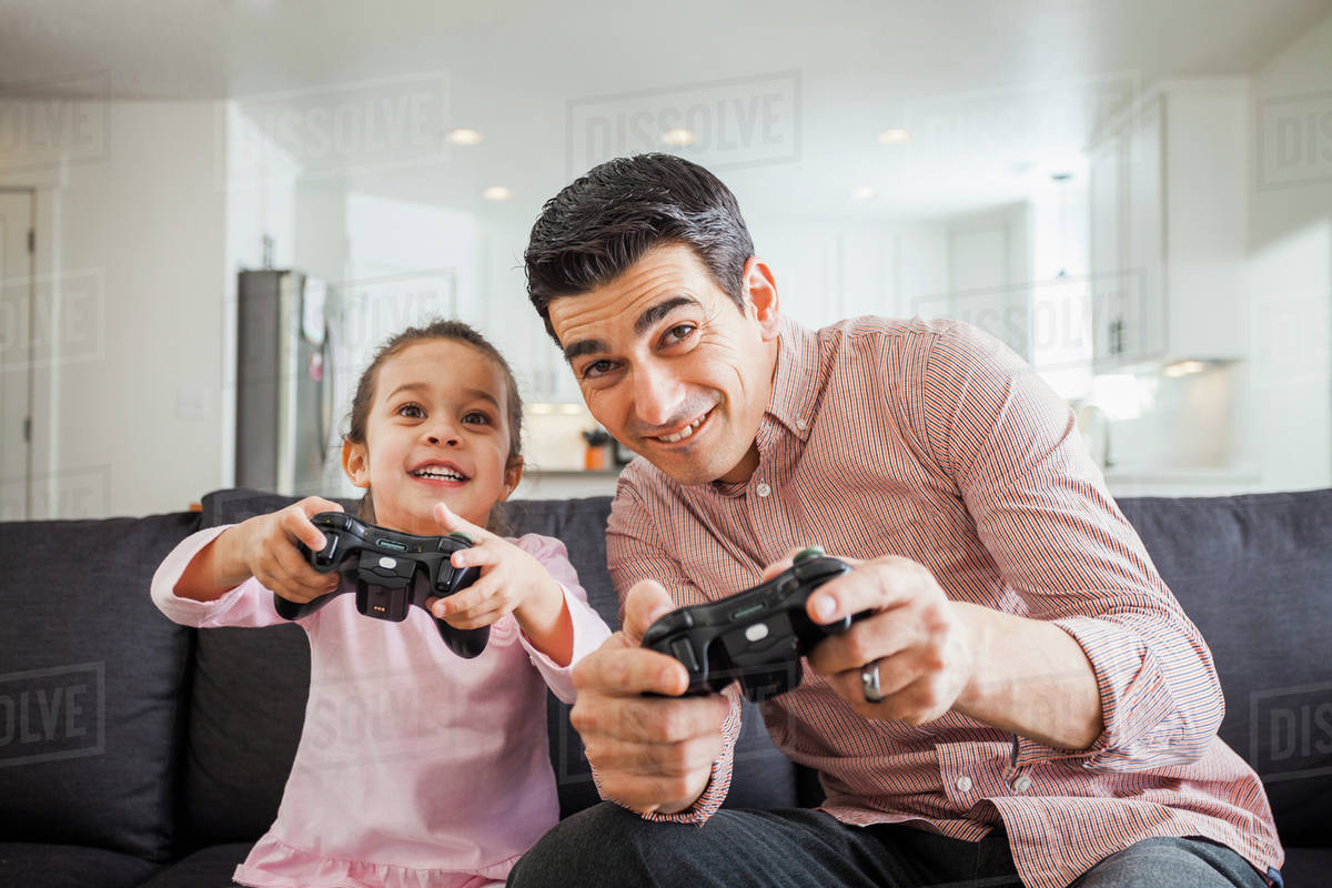 Father and daughter playing video games in living room - Royalty-free ...