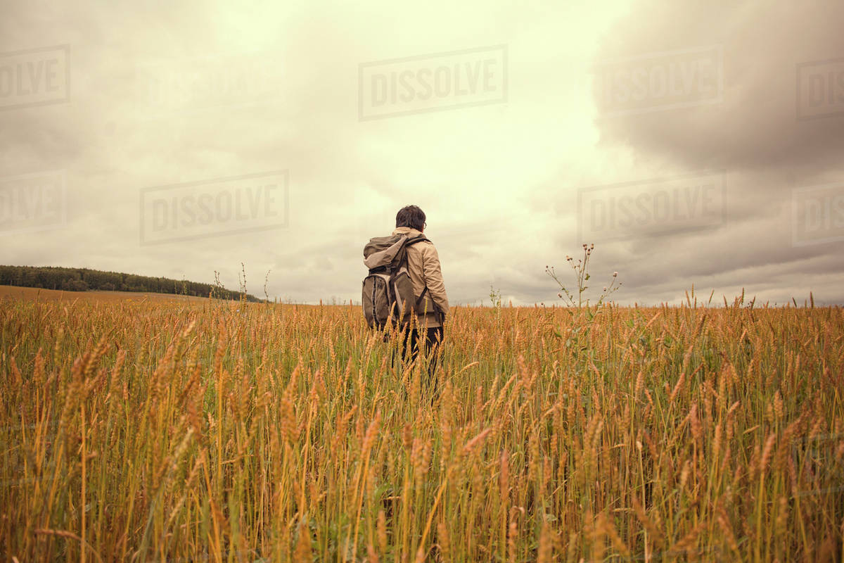 Mari man standing in tall grass in rural field - Stock Photo - Dissolve