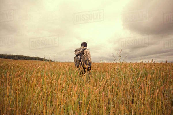 Mari man standing in tall grass in rural field - Stock Photo - Dissolve