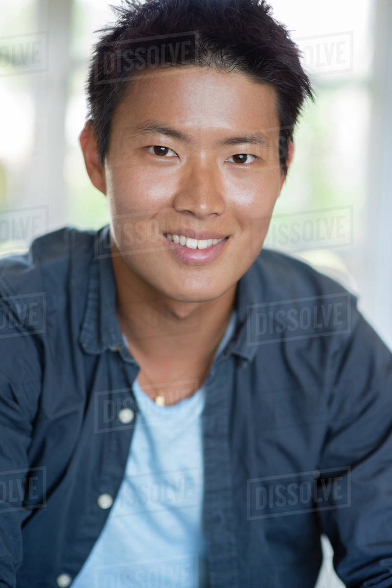 Korean man smiling indoors - Royalty-free Stock Photo | Dissolve