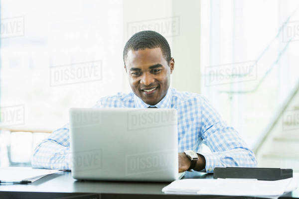 Black businessman using laptop computer at desk in office - Royalty ...