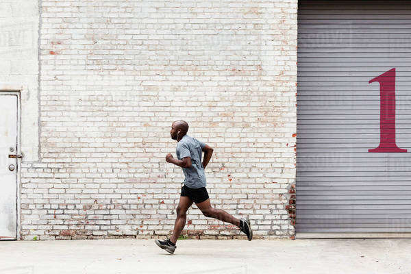 Black man running on city sidewalk - Royalty-free Stock Photo | Dissolve