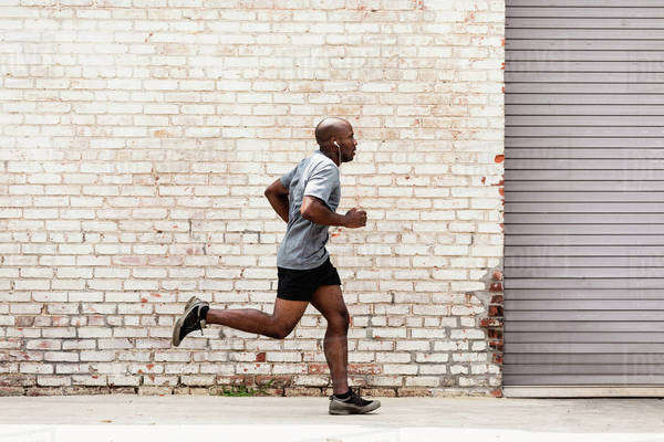 Black man running on city sidewalk - Royalty-free Stock Photo | Dissolve