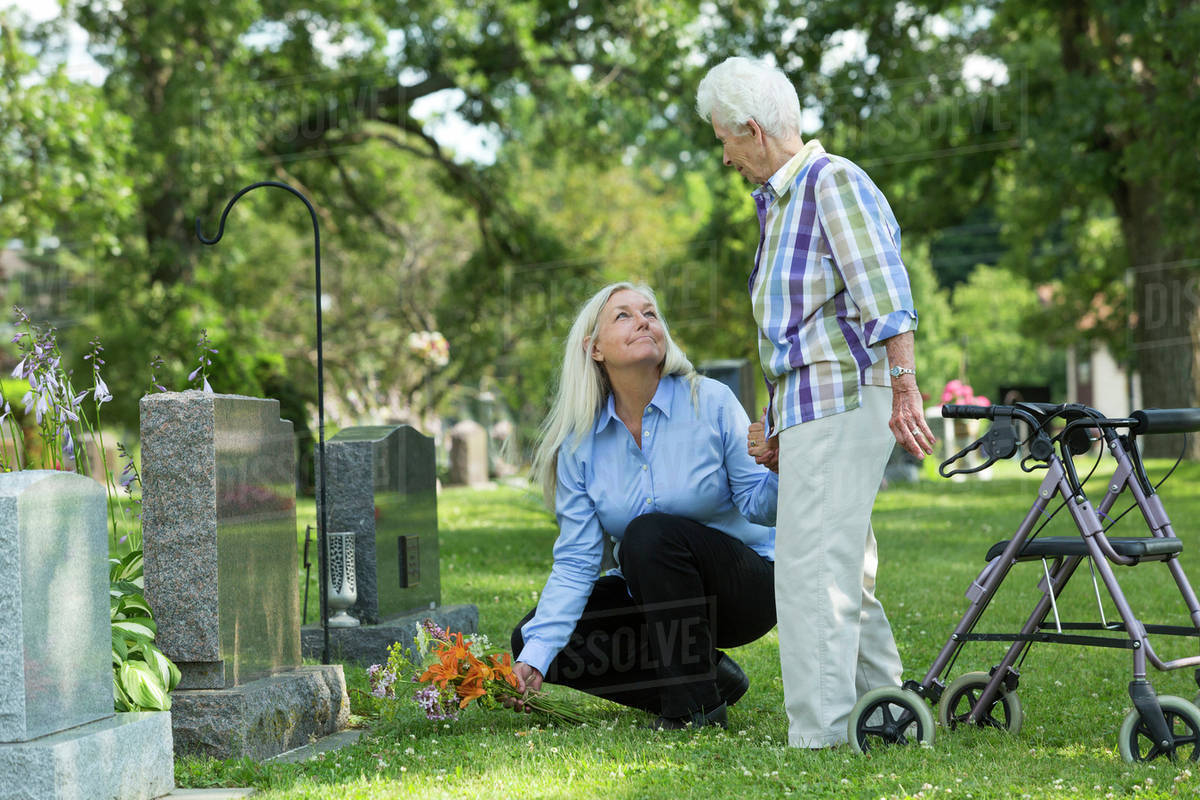 Caucasian mother and daughter visiting grave in cemetery - Royalty-free ...
