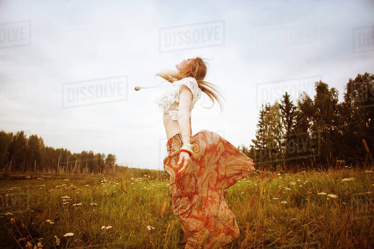 Caucasian woman dancing in field - Royalty-free Stock Photo | Dissolve