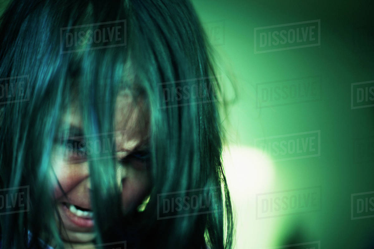 Angry mixed race girl peering up through hair - Stock Photo - Dissolve