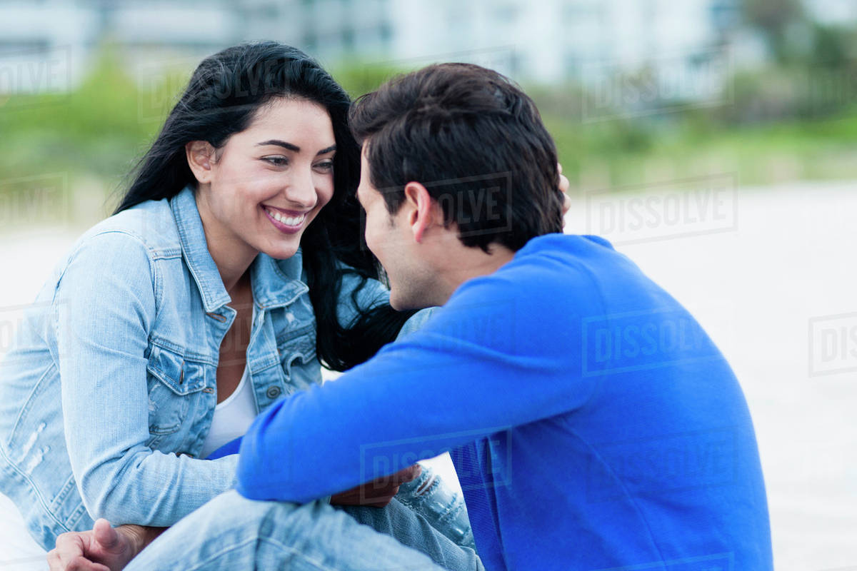 Hispanic couple talking on beach - Royalty-free Stock Photo | Dissolve