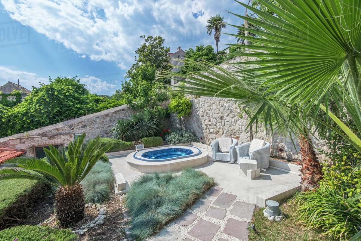 Soaking pool and armchairs on hillside patio - Stock Photo - Dissolve