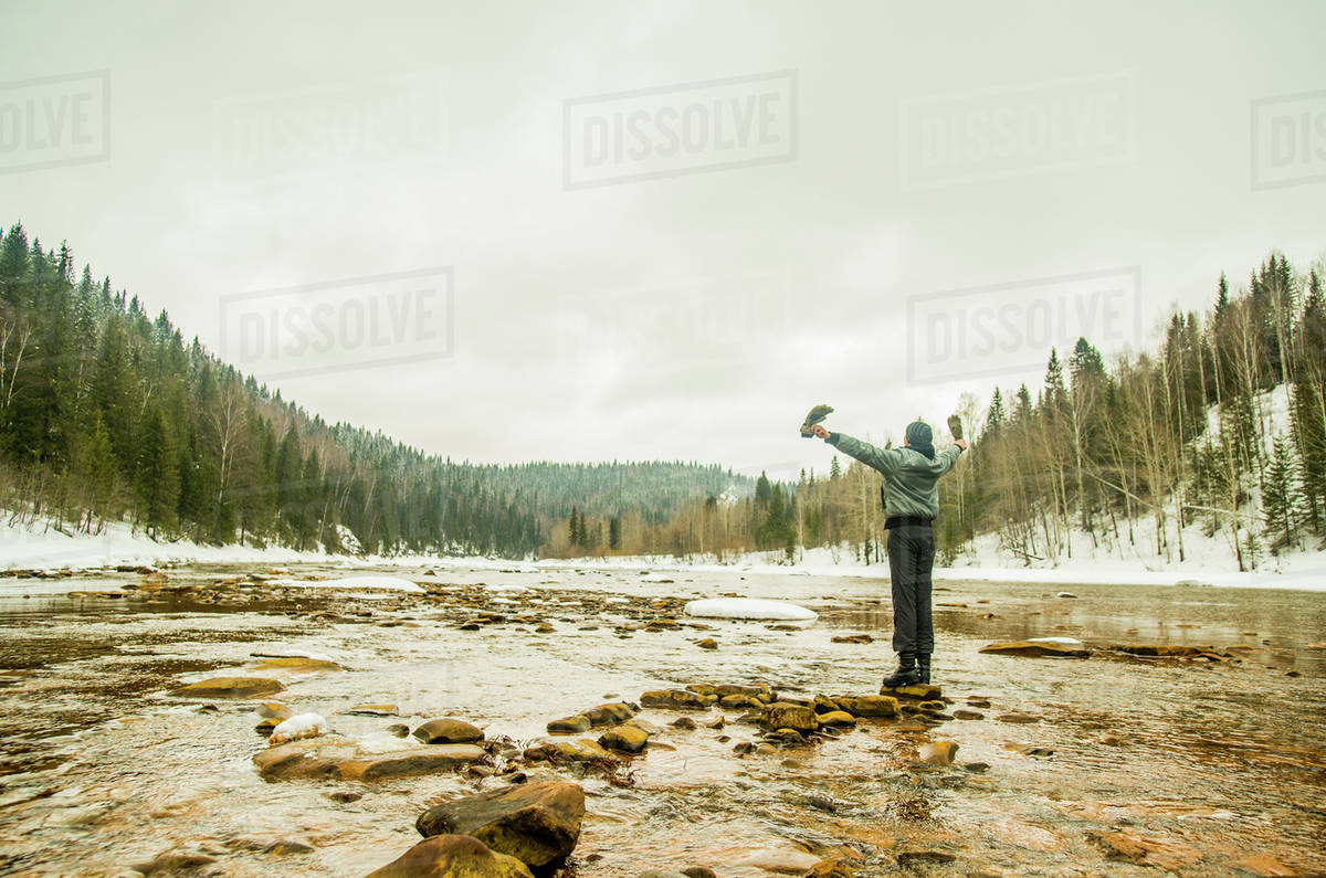 Caucasian hiker with arms outstretched standing in remote river ...