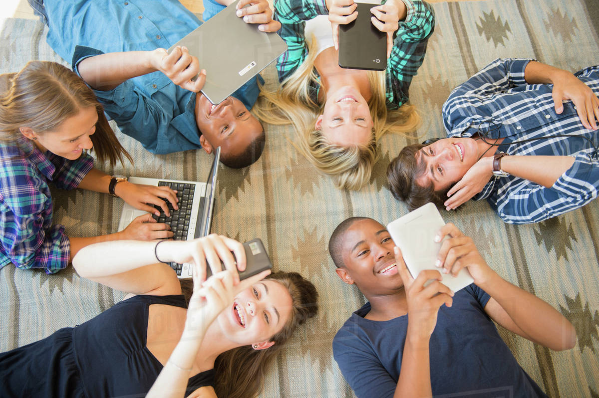 Teenagers laying on floor using technology - Stock Photo - Dissolve