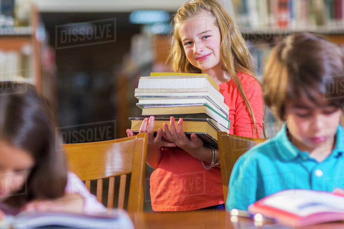 Student carrying stack of books in library - Royalty-free Stock Photo ...