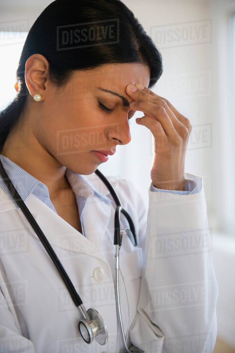 Indian doctor rubbing her forehead - Royalty-free Stock Photo | Dissolve