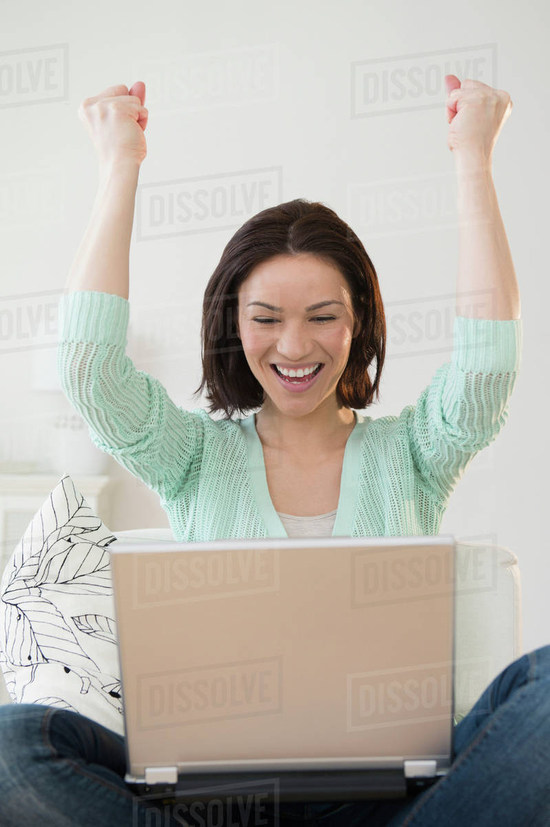 Caucasian woman cheering at laptop - Royalty-free Stock Photo | Dissolve