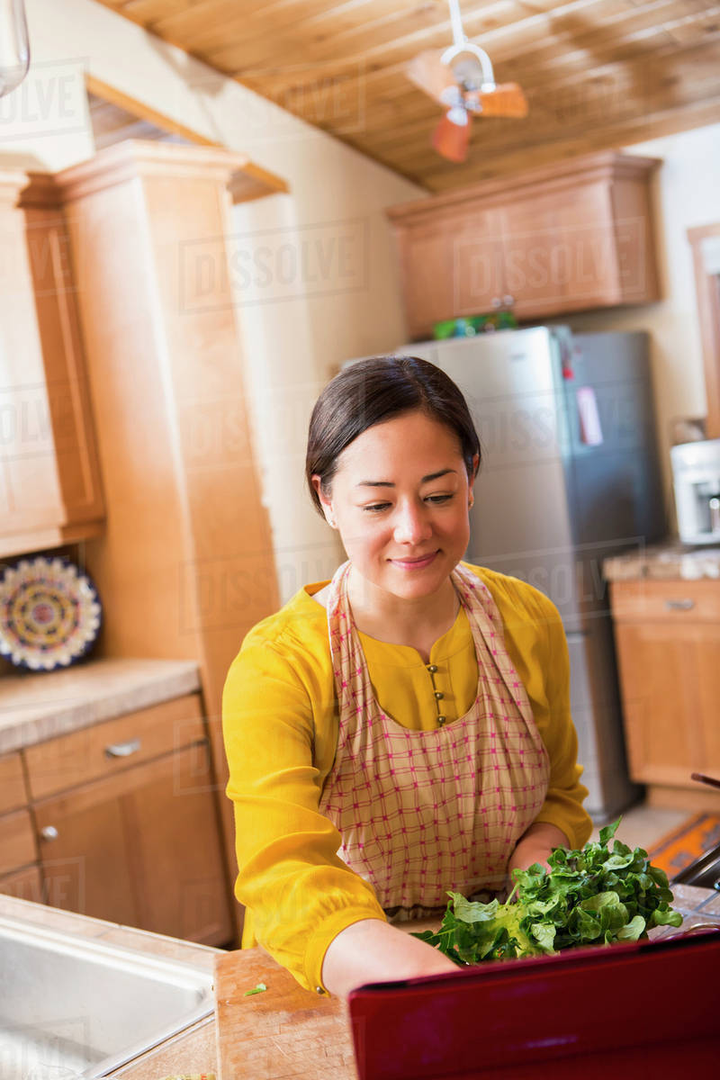 Mixed race woman cooking in kitchen - Royalty-free Stock Photo | Dissolve