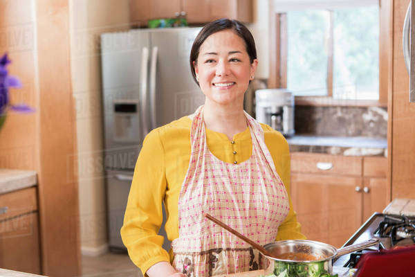 Mixed race woman cooking in kitchen - Royalty-free Stock Photo | Dissolve