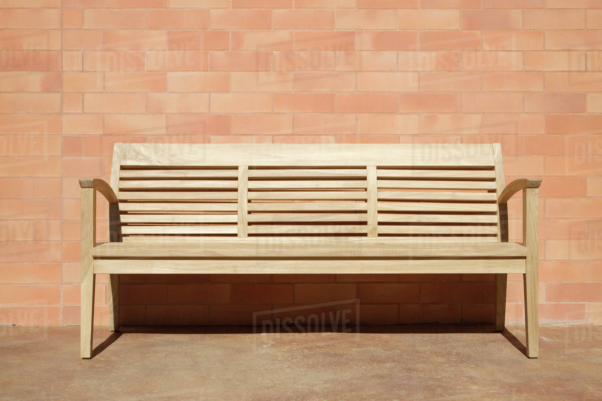 Wooden Bench Set Against Brick Wall - Stock Photo - Dissolve