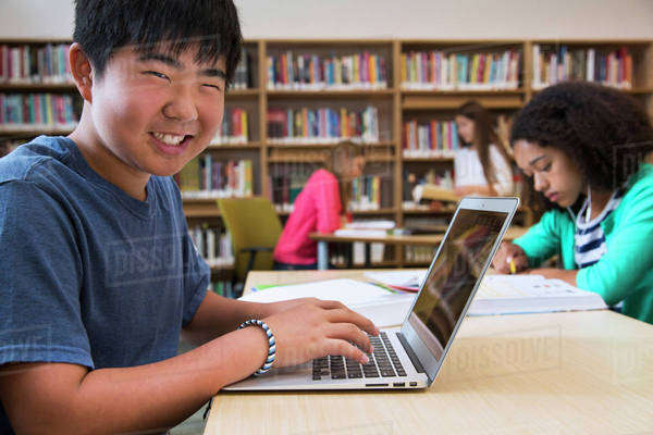 Student using laptop in library - Stock Photo - Dissolve