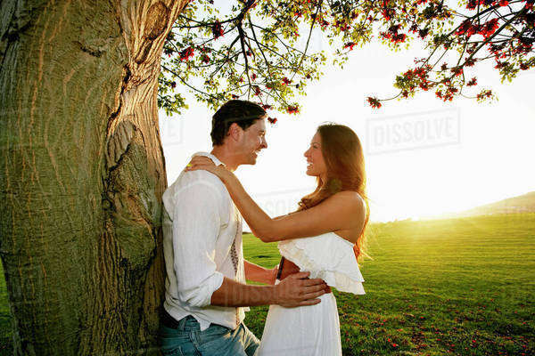 Couple hugging by tree in park - Stock Photo - Dissolve