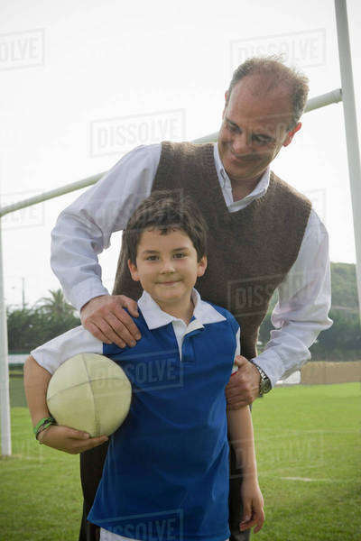Hispanic man smiling with son on field - Stock Photo - Dissolve