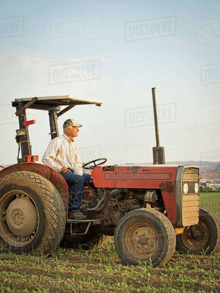 Caucasian farmer driving tractor in crop field - Royalty-free Stock ...
