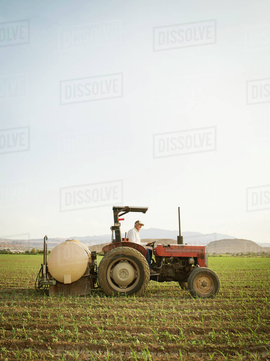 Caucasian farmer driving tractor in crop field - Stock Photo - Dissolve