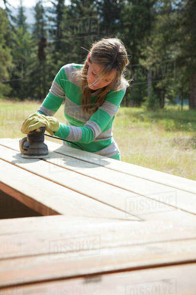 Caucasian woman sanding wood outdoors - Royalty-free Stock Photo | Dissolve